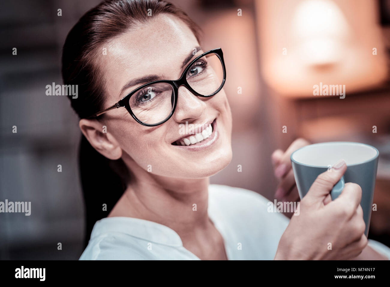 Cute bespectacled woman smiling and drinking tea Stock Photo - Alamy