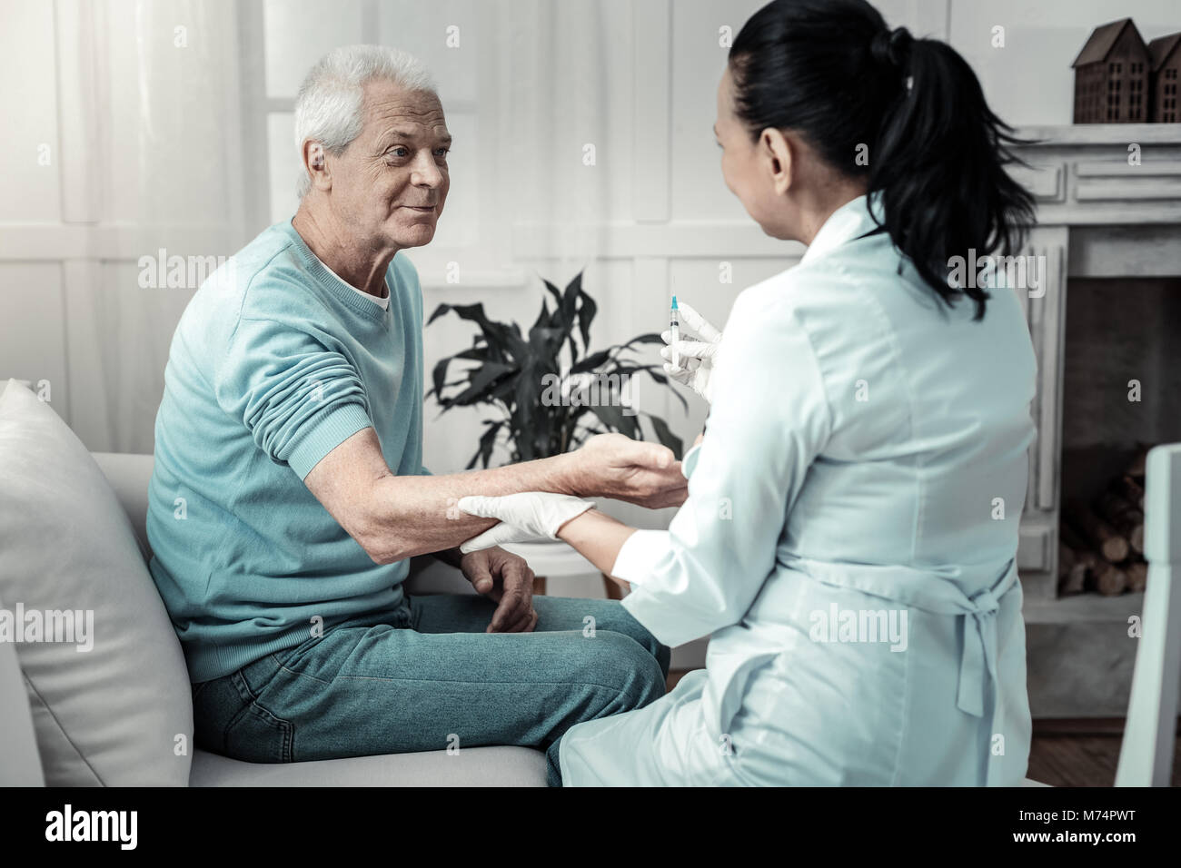 Pleasant kind man looking at the doctor giving her arm Stock Photo - Alamy