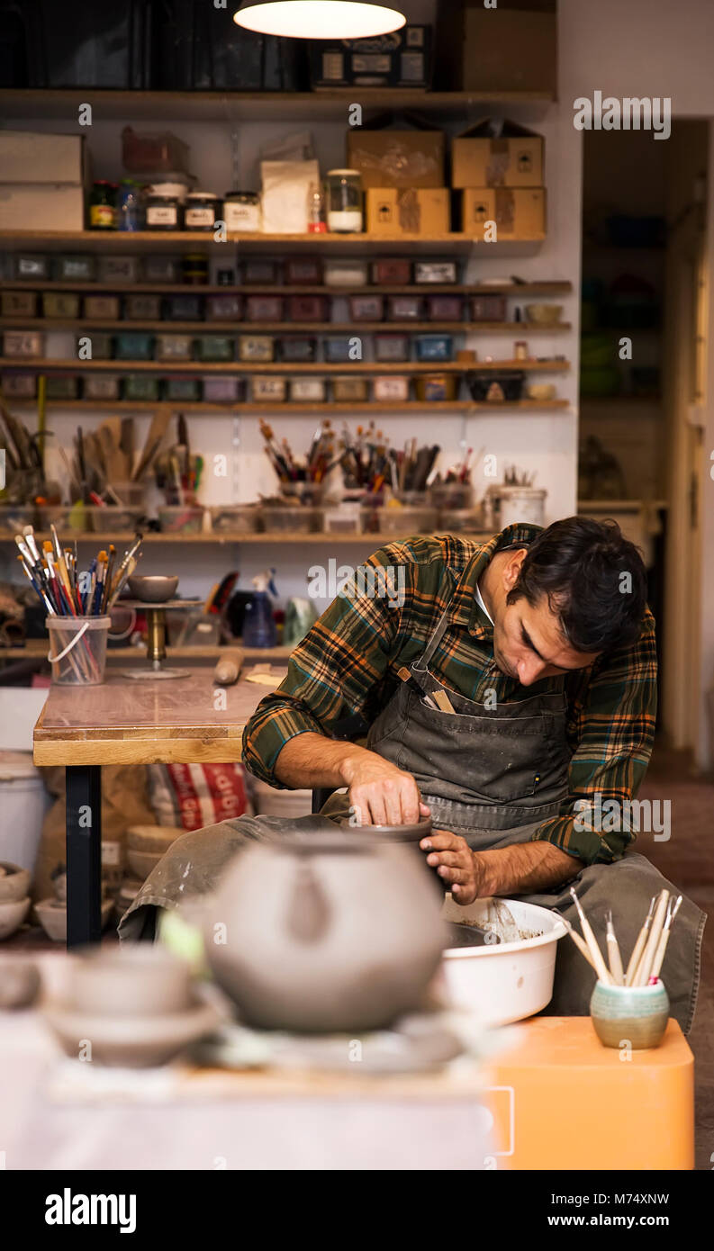 View at an artist makes clay pottery on a spin wheel Stock Photo - Alamy