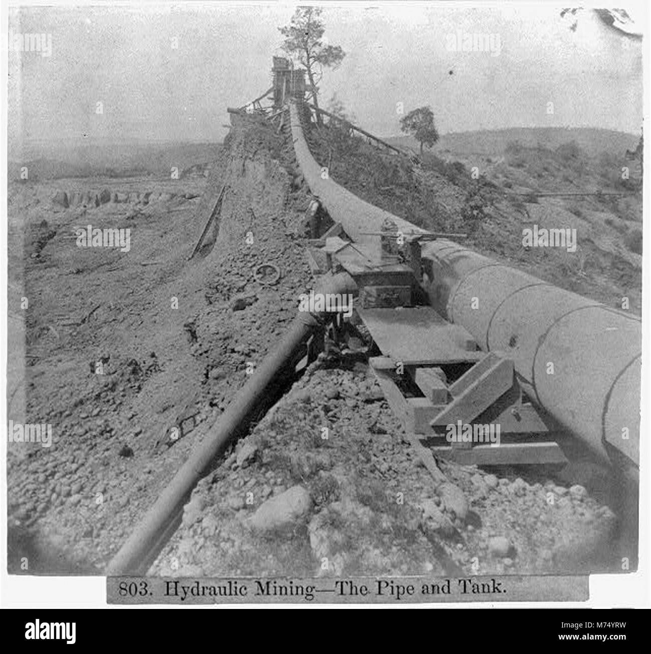 The image depicts hydraulic mining operations, showing a pipe and tank ...