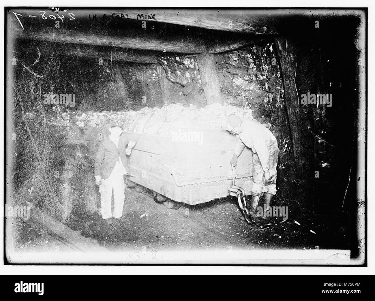 The photograph depicts workers inside a coal mine, capturing the ...