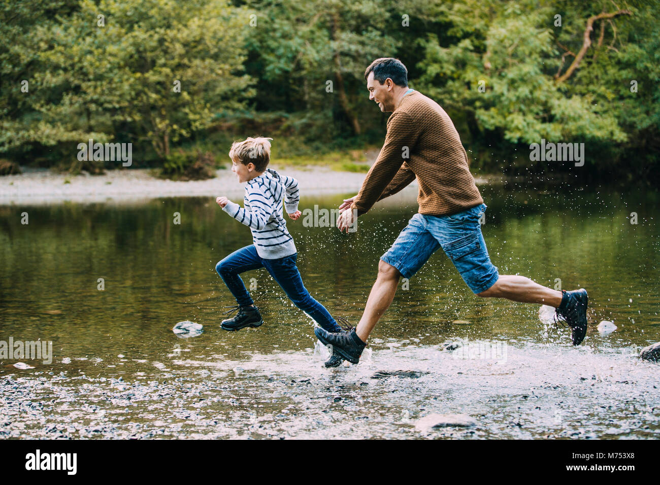 Little boy is being chased in to the lake by his father while they are ...