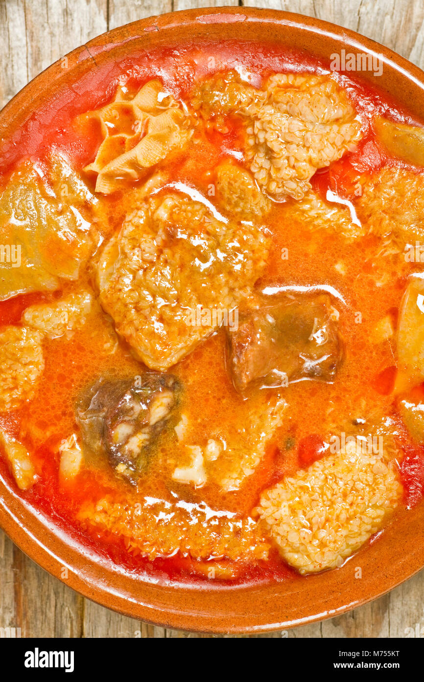 Close up of Spanish callos in an earthenware dish on a wooden table ...