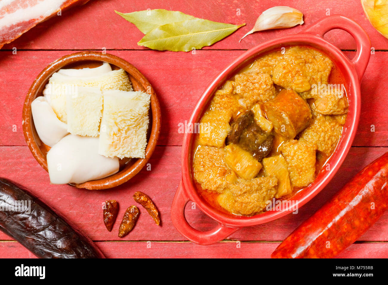 Spanish callos on a red bowl and ingredients on a red wooden table ...