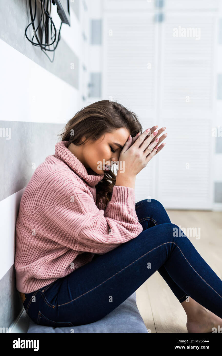 Young woman after cry sitting on whte floor at home in depression. A ...