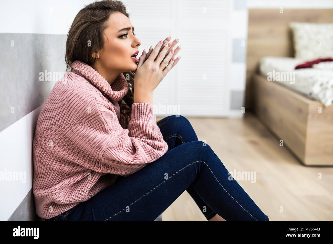 Young woman after cry sitting on whte floor at home in depression. A ...