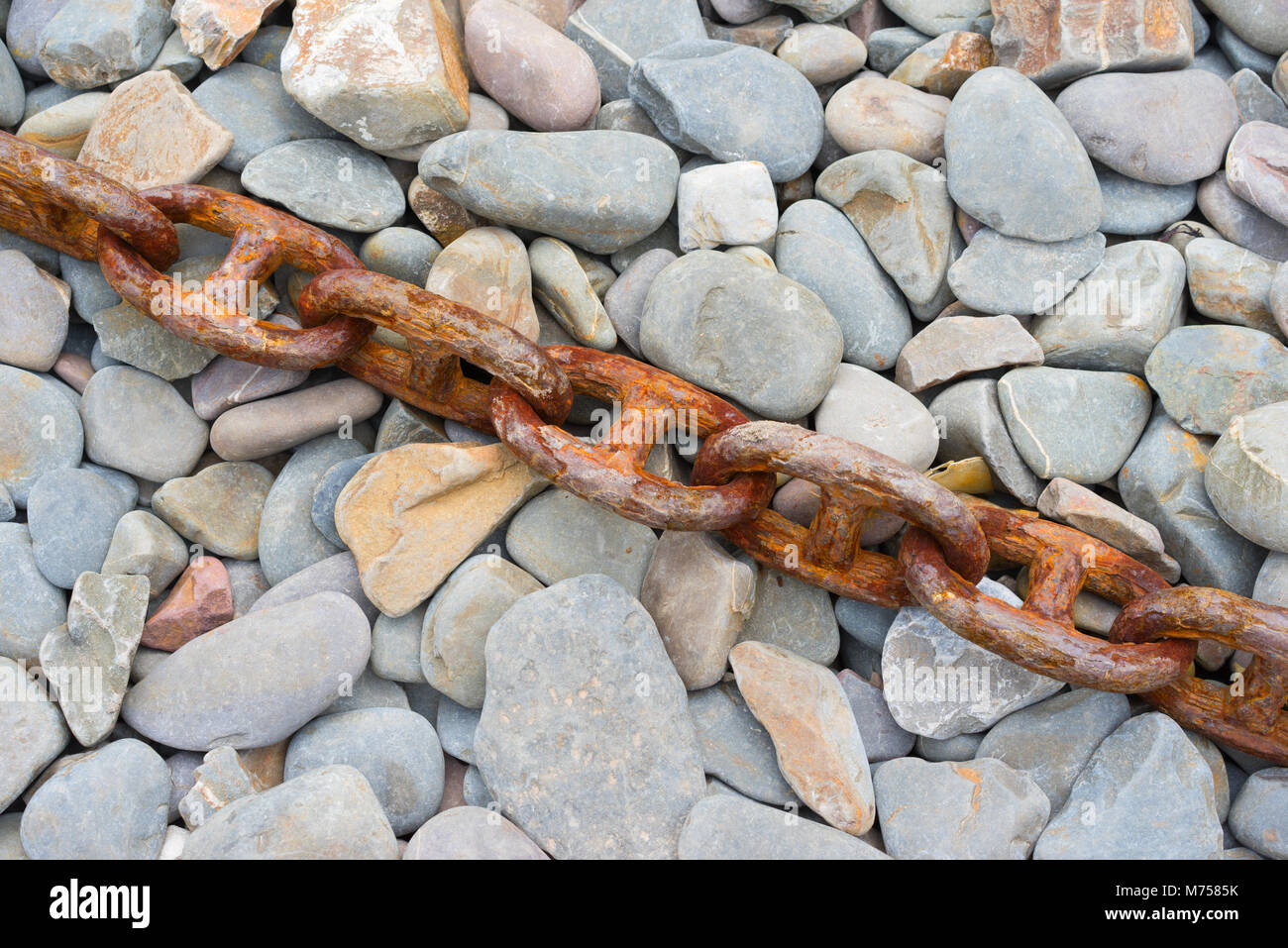 Heavy wieght rusty chains over pebbles and stones in Harbour Stock ...