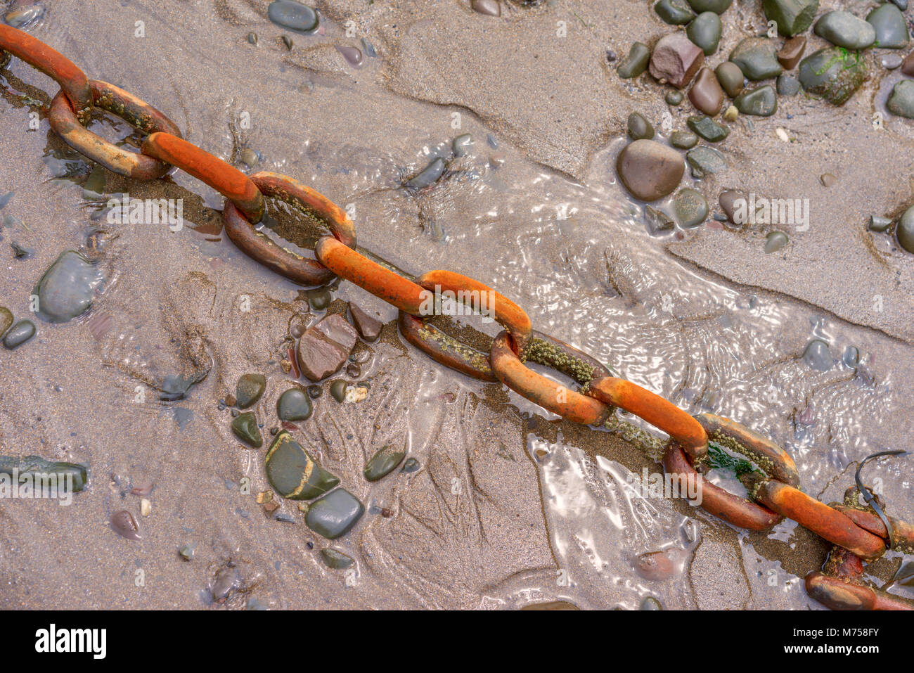 Heavy wieght rusty chains over pebbles and stones in Harbour Stock ...
