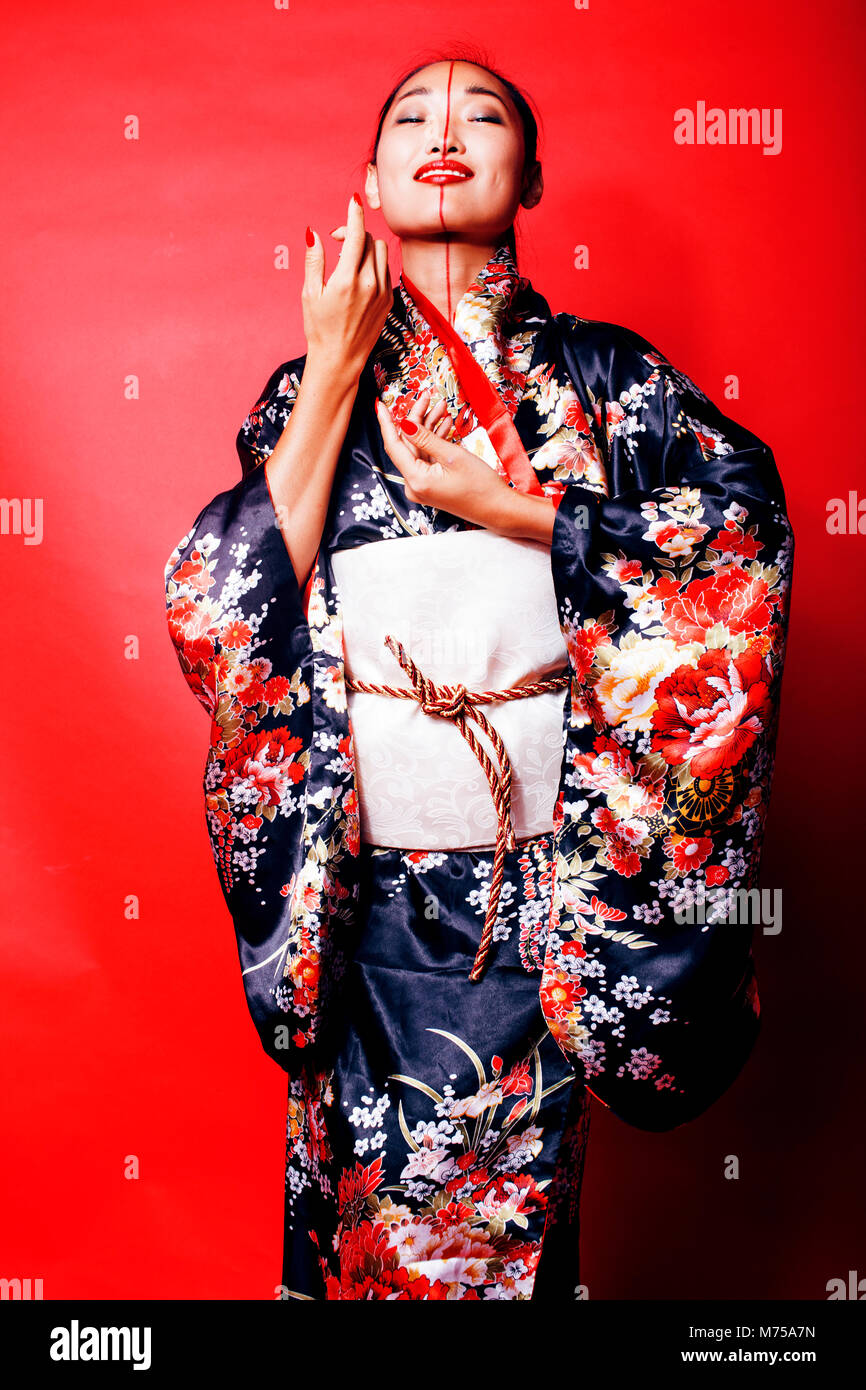young pretty geisha on red background posing in kimono, oriental people ...