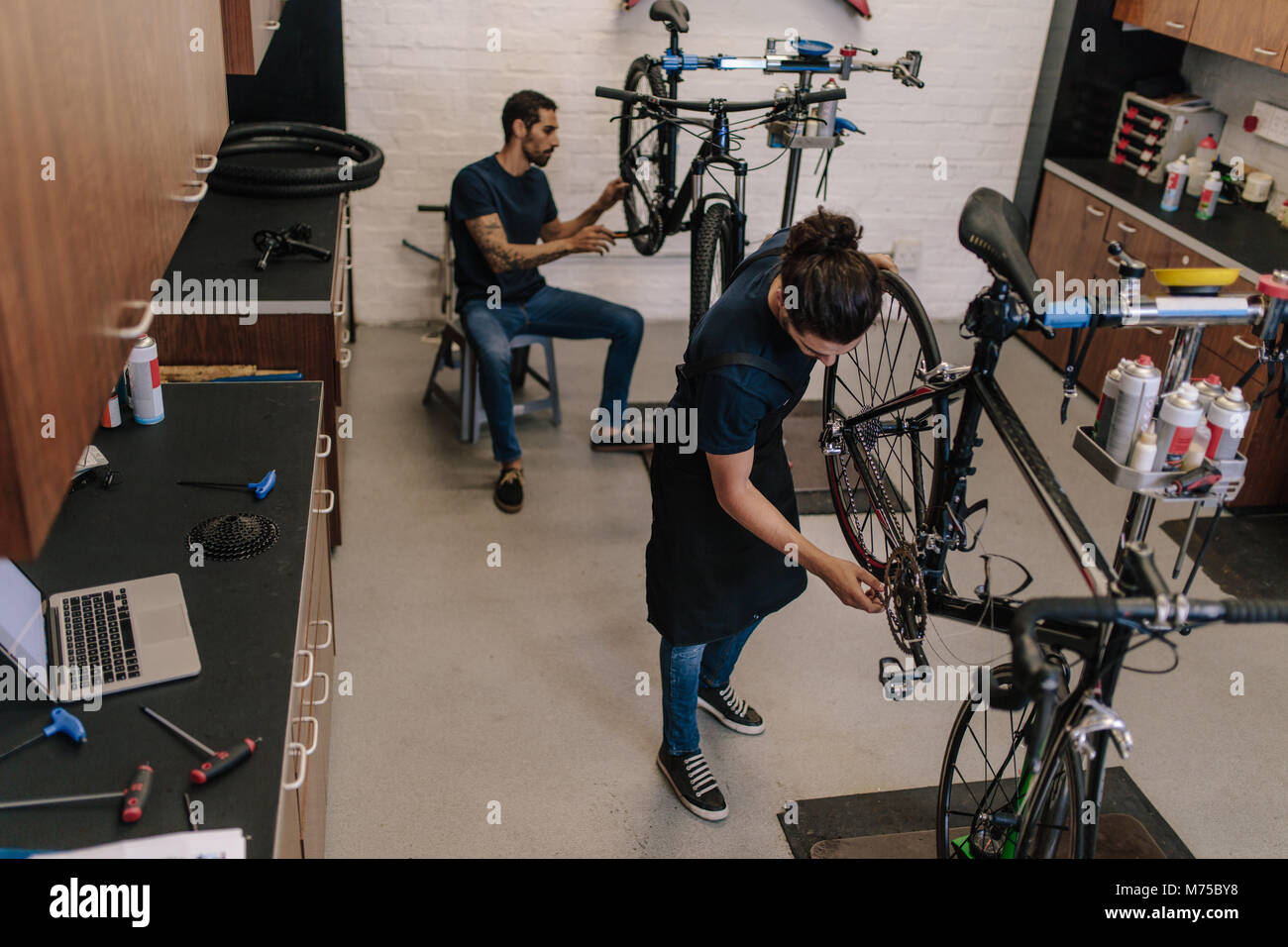 Workers repairing bicycles in a cycle shop. Mechanics assembling ...