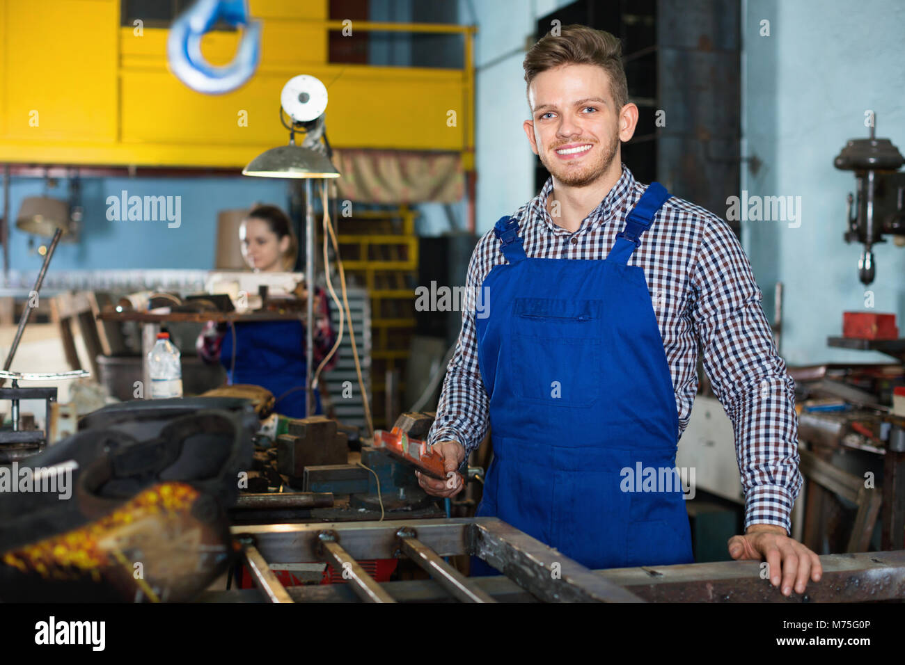 Portrait of glad cheerful smiling master who is posing on his workplace ...
