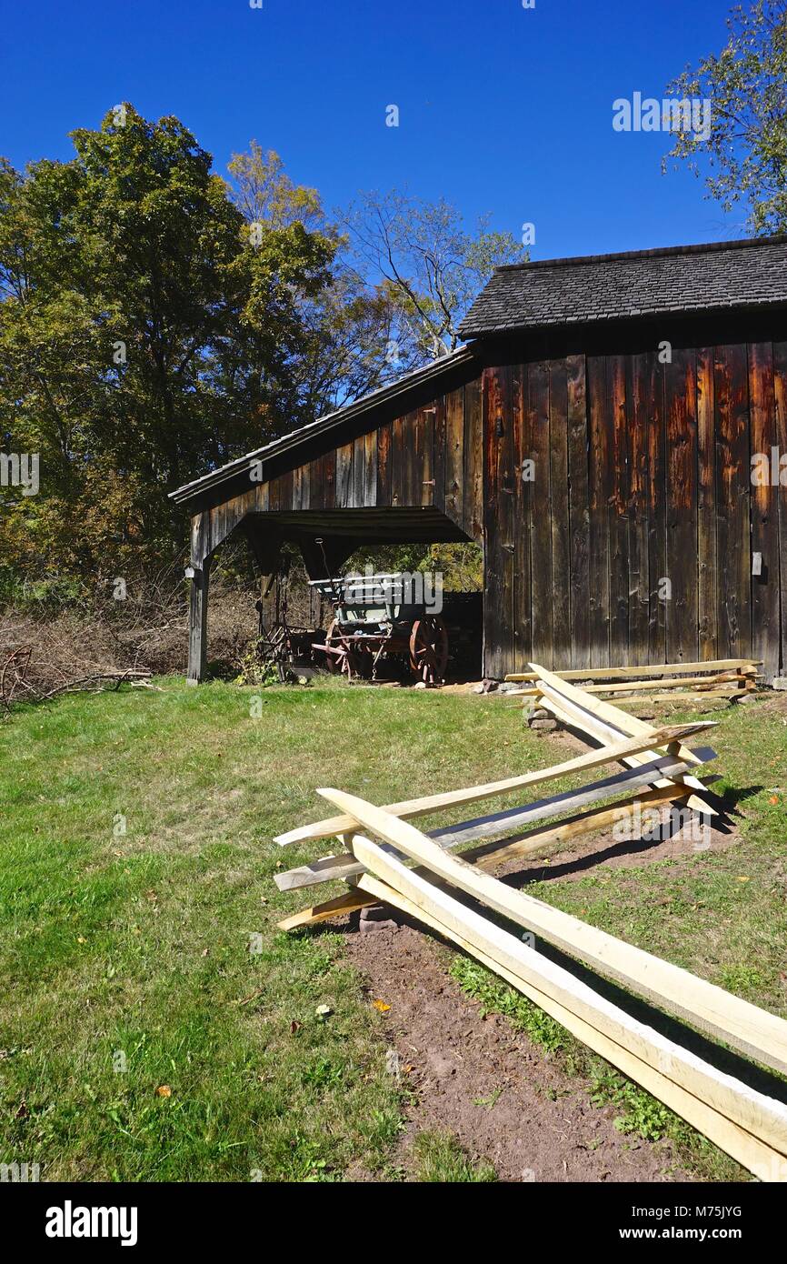 A split-log fence leads to an old wooden barn with a shed and an ...