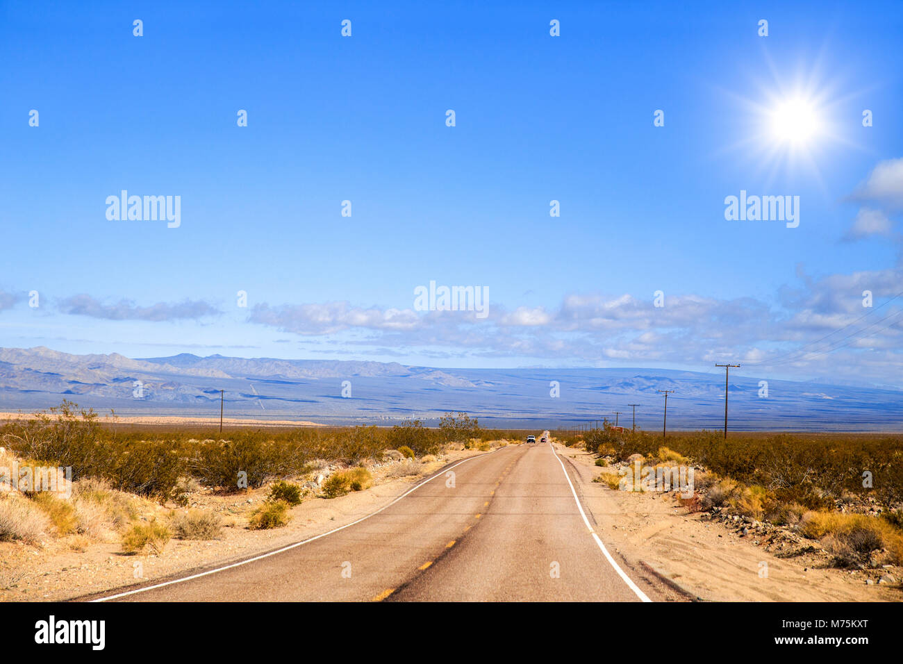 A long narrow stretching across a flat desert floor with mountains in ...