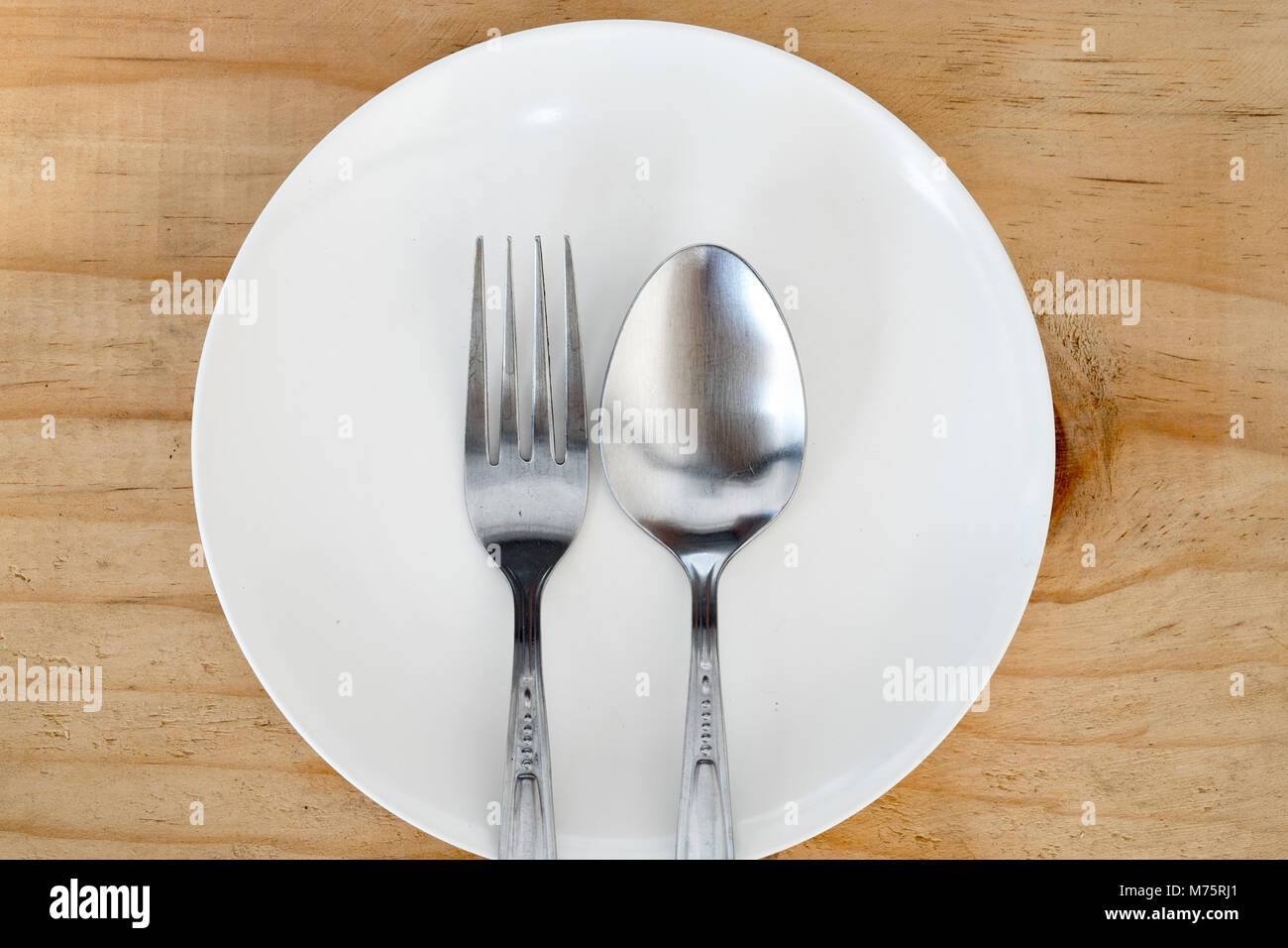 Dining set including spoon, fork and plate on wooden table Stock Photo ...