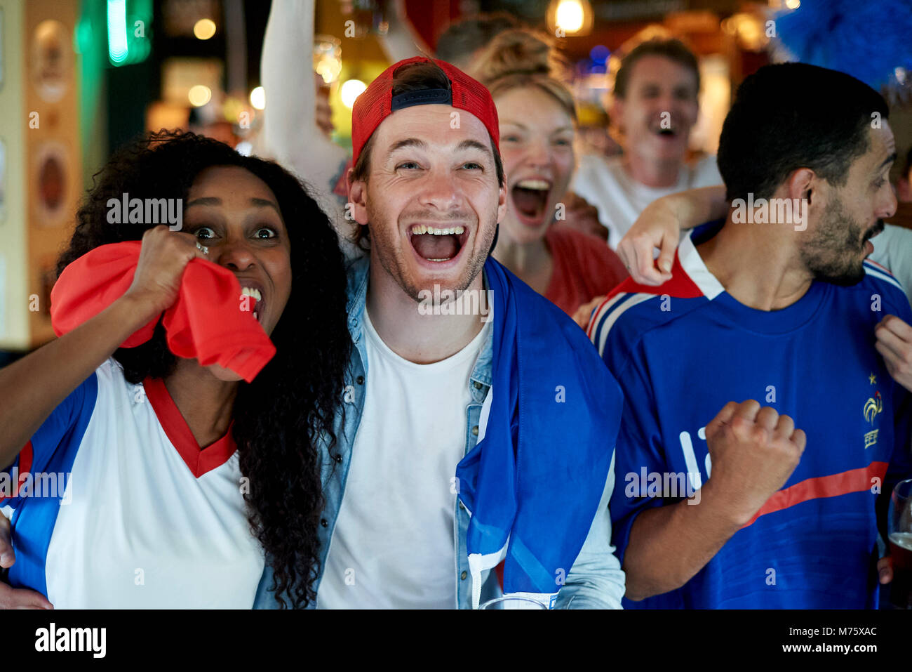 French football fans watching soccer match on television at pub Stock ...