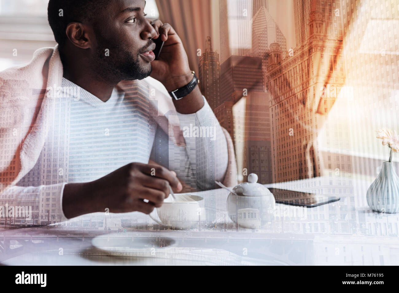 Concentrated young man looking into the window while talking on the ...