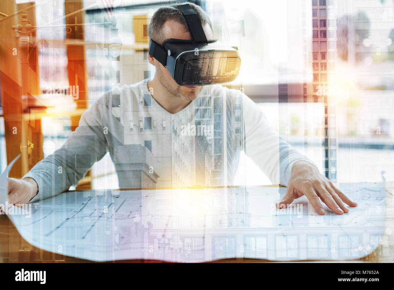 Smart architect sitting with a drawing while wearing virtual reality ...