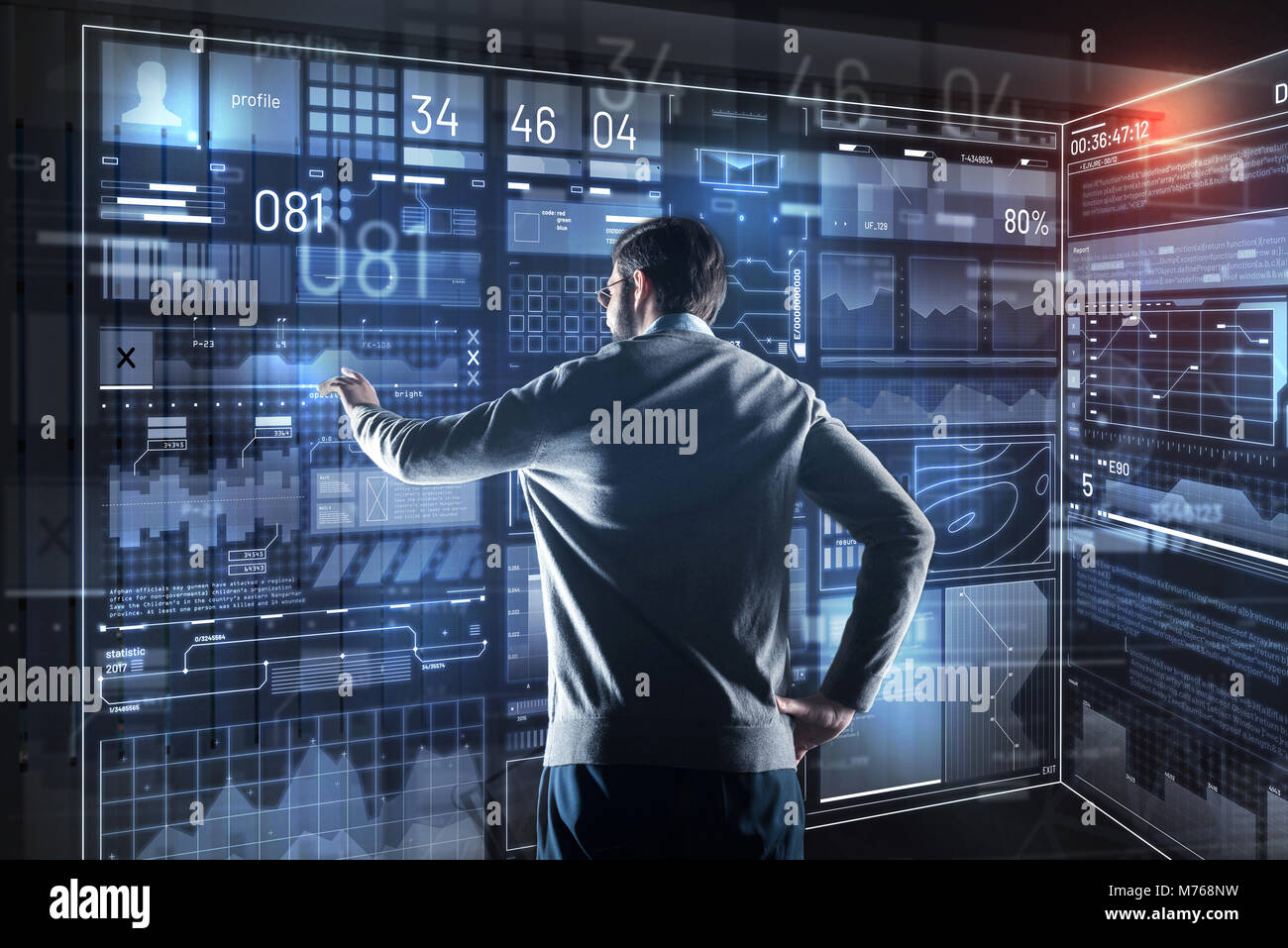 Careful programmer looking at screen of his device while studying information Stock Photo - Alamy