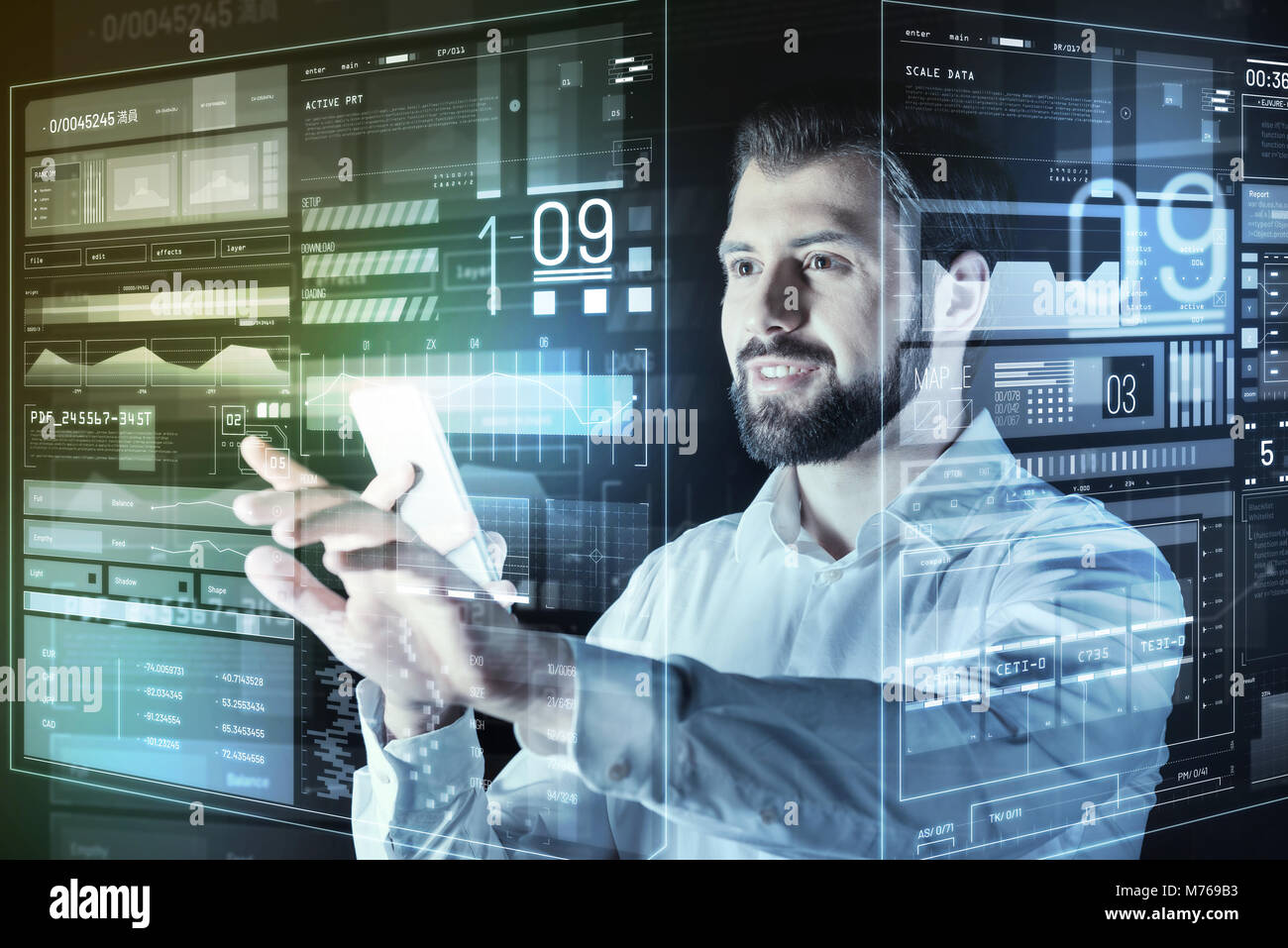 Handsome programmer holding a smartphone and looking at the screen of ...