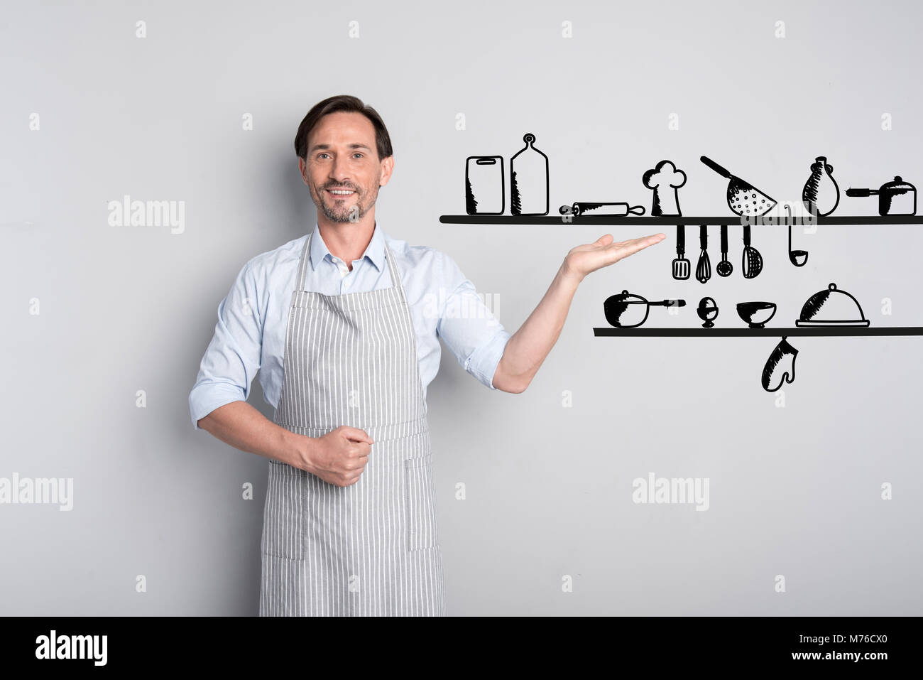 Cheerful cook smiling while showing his dishes on a shelf Stock Photo ...