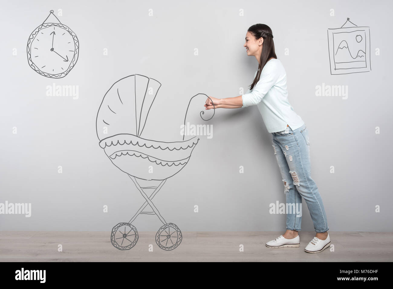 Young woman dreaming of becoming a mother and imagining a baby carriage ...