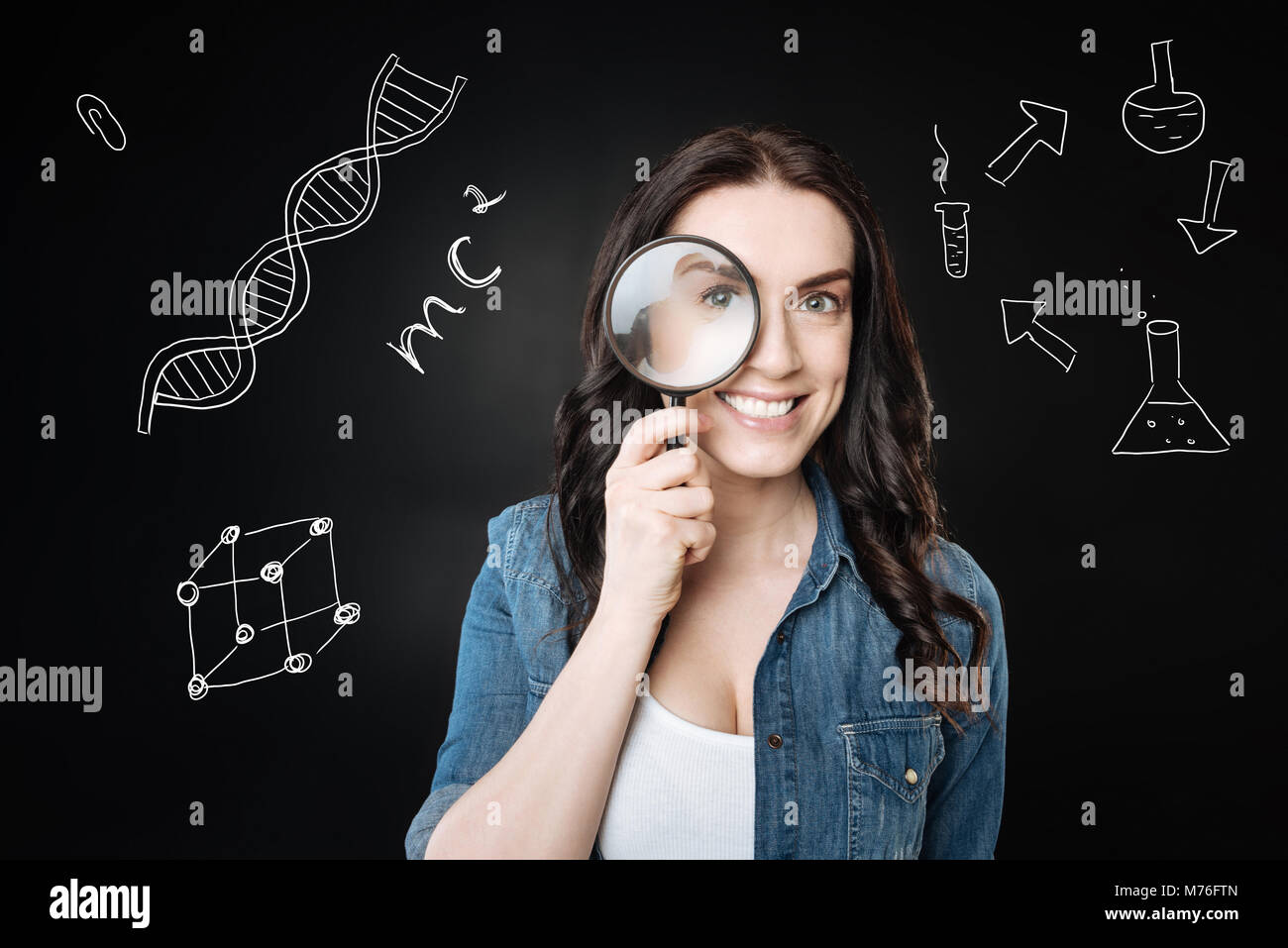 Cheerful student looking through the magnifying glass and smiling Stock ...
