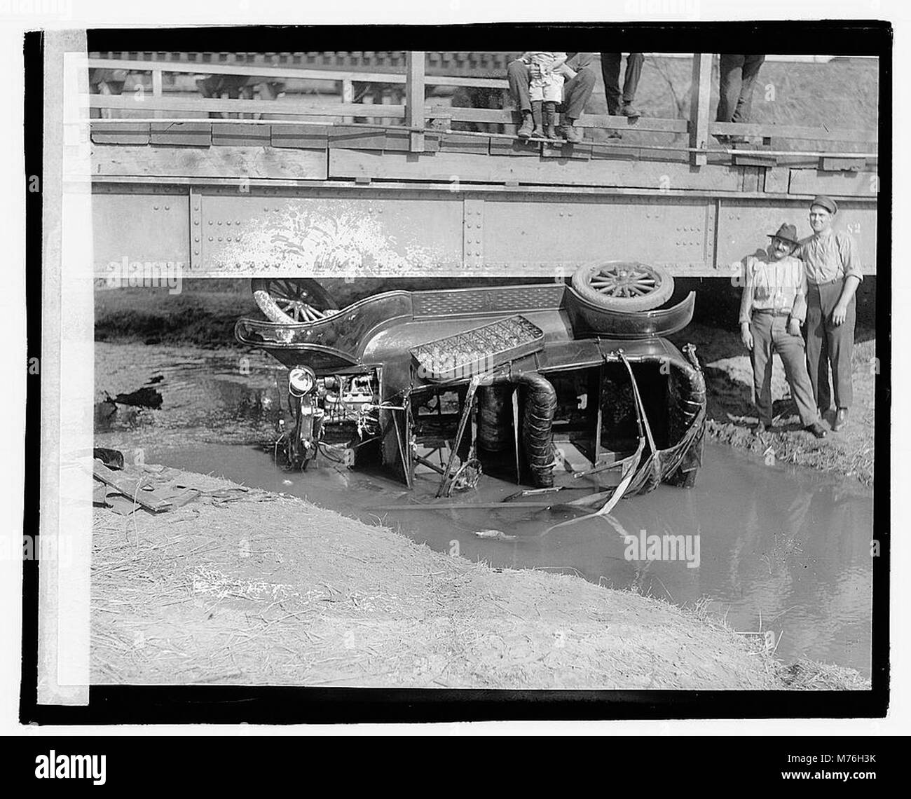 This photograph depicts the aftermath of an auto wreck, showing a car ...
