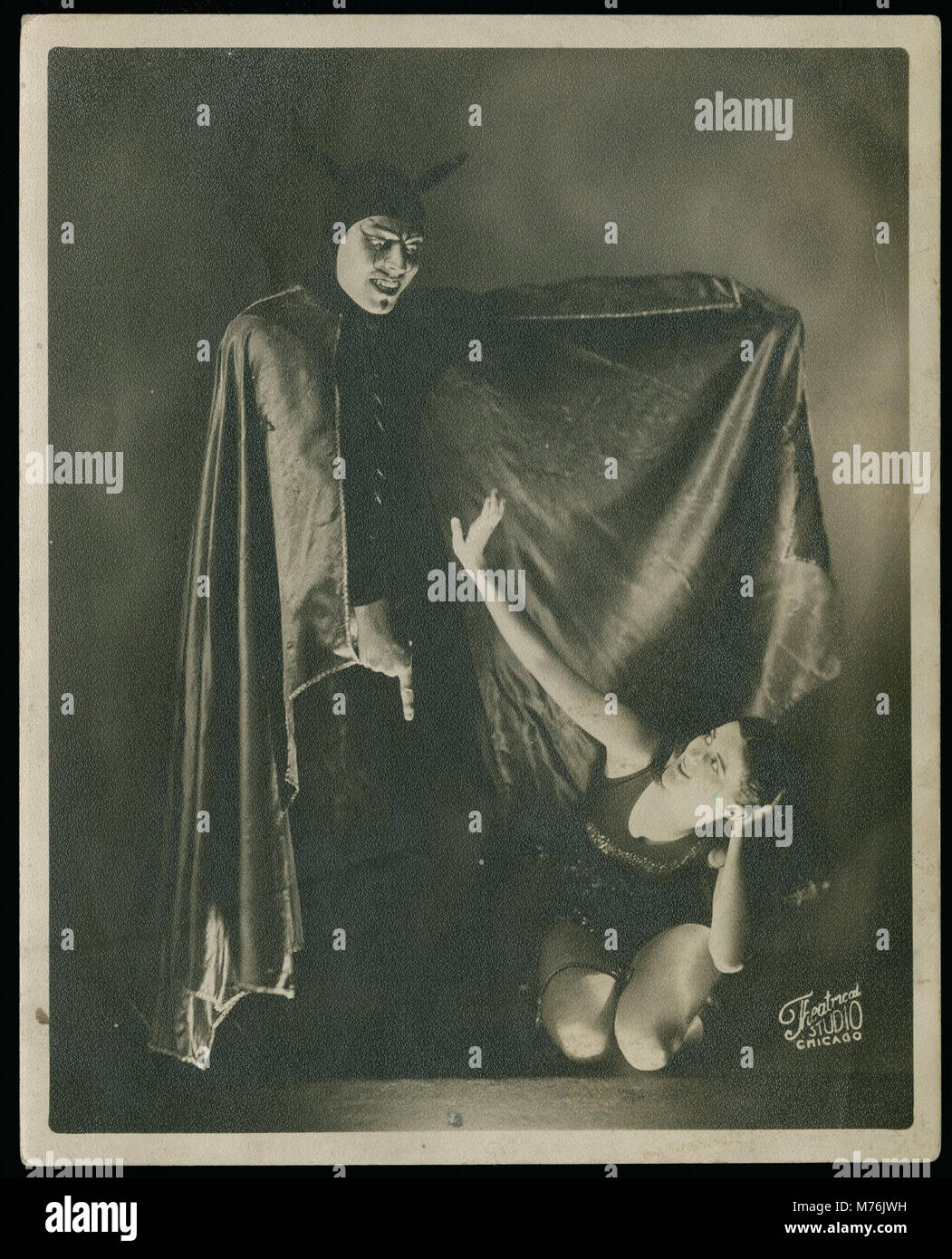 A dramatic scene from a play depicting the devil with a kneeling woman ...