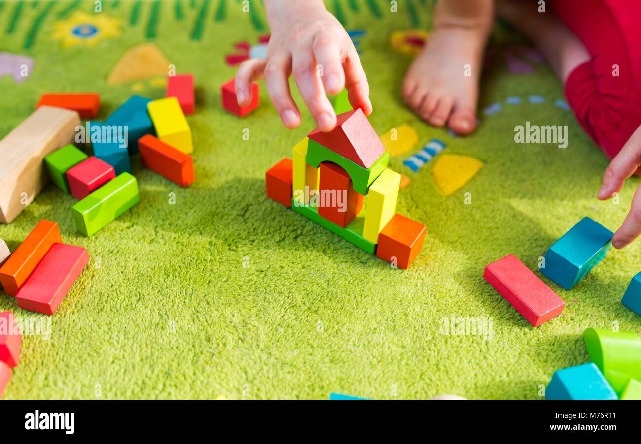 Small child playing with wooden blocks on green carpet - shallow depth ...