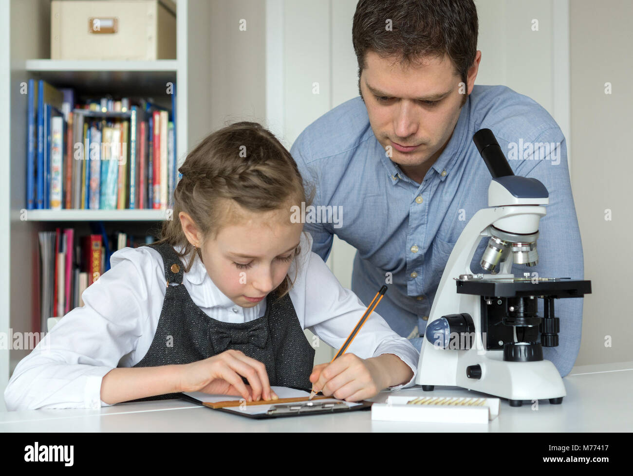 Little girl with teacher in science class with microscope on the table ...