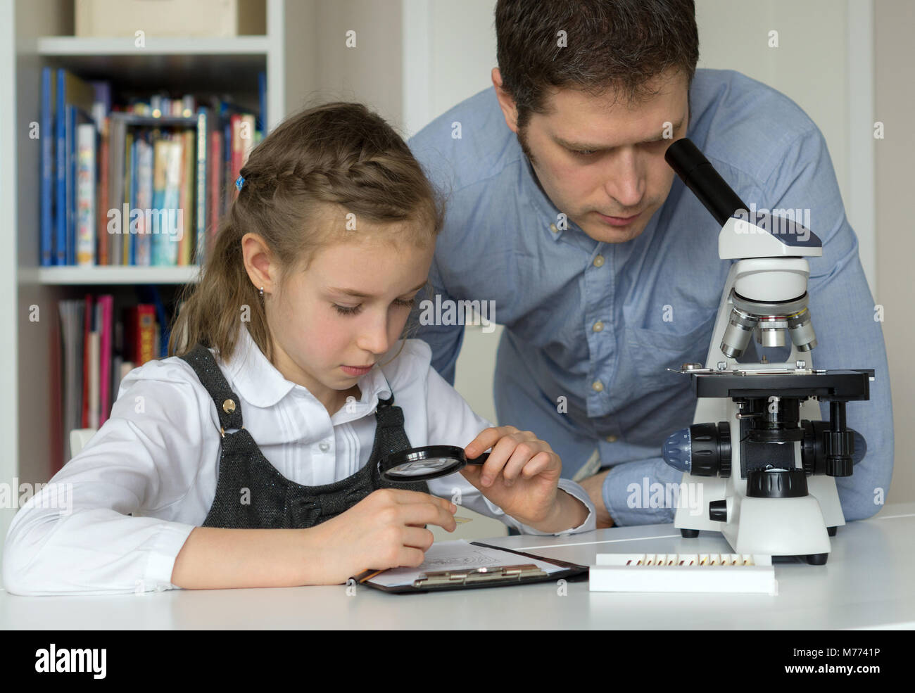 Little girl with teacher in science class with microscope on the table ...