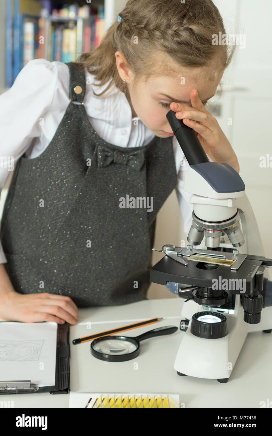 Little girl in science class using microscope Stock Photo - Alamy