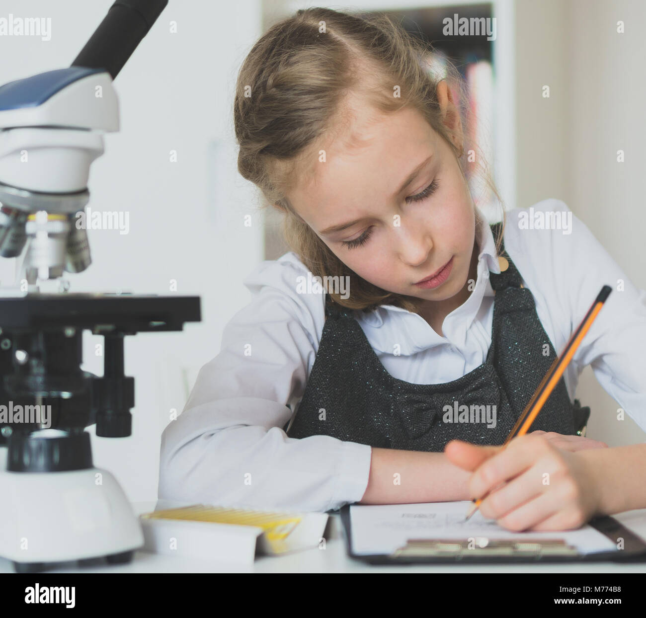 Little girl in science class with microscope on the table Stock Photo ...