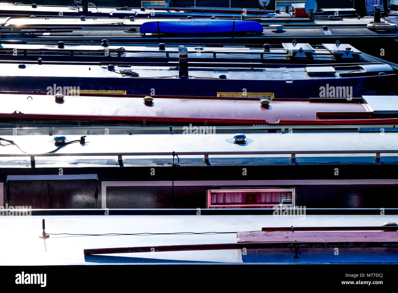 twelve long traditional british blue and red canal boats moored ...