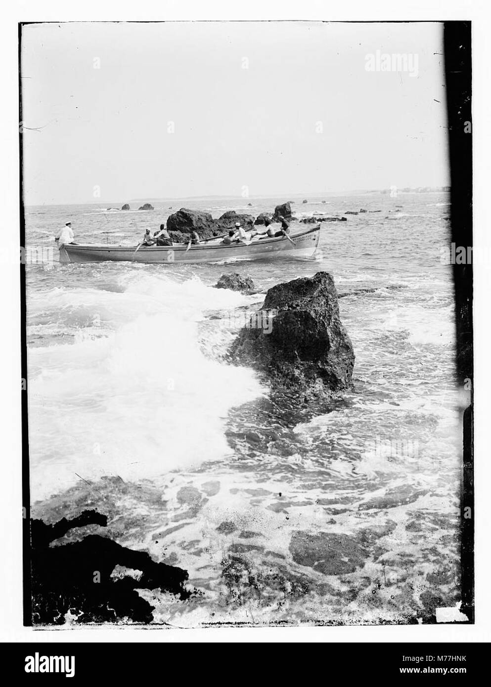A photograph of a boat passing rocks near Jaffa, capturing the coastal ...