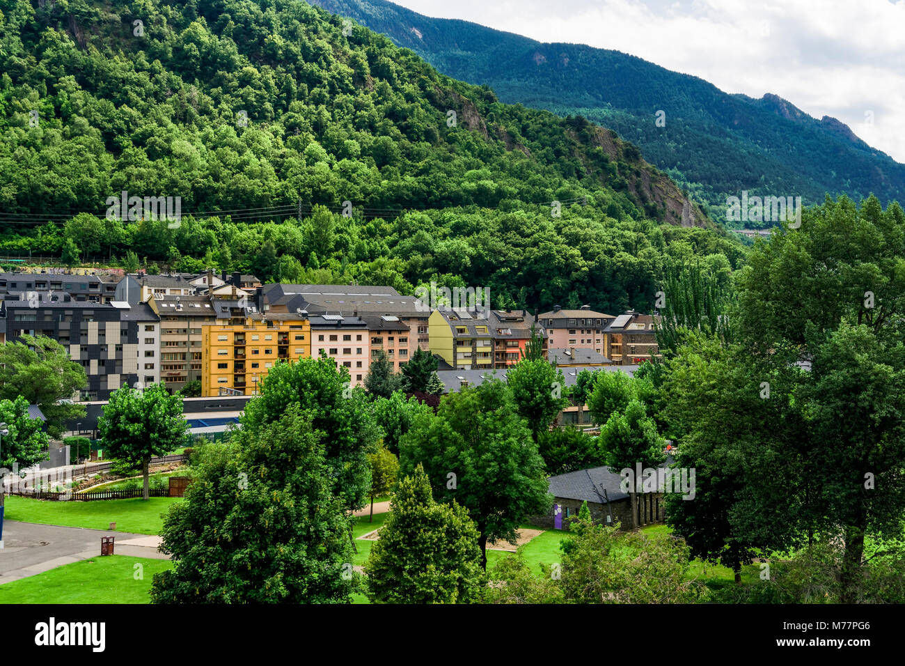 Day view of local buildings by a green hill in Andorra la Vella ...