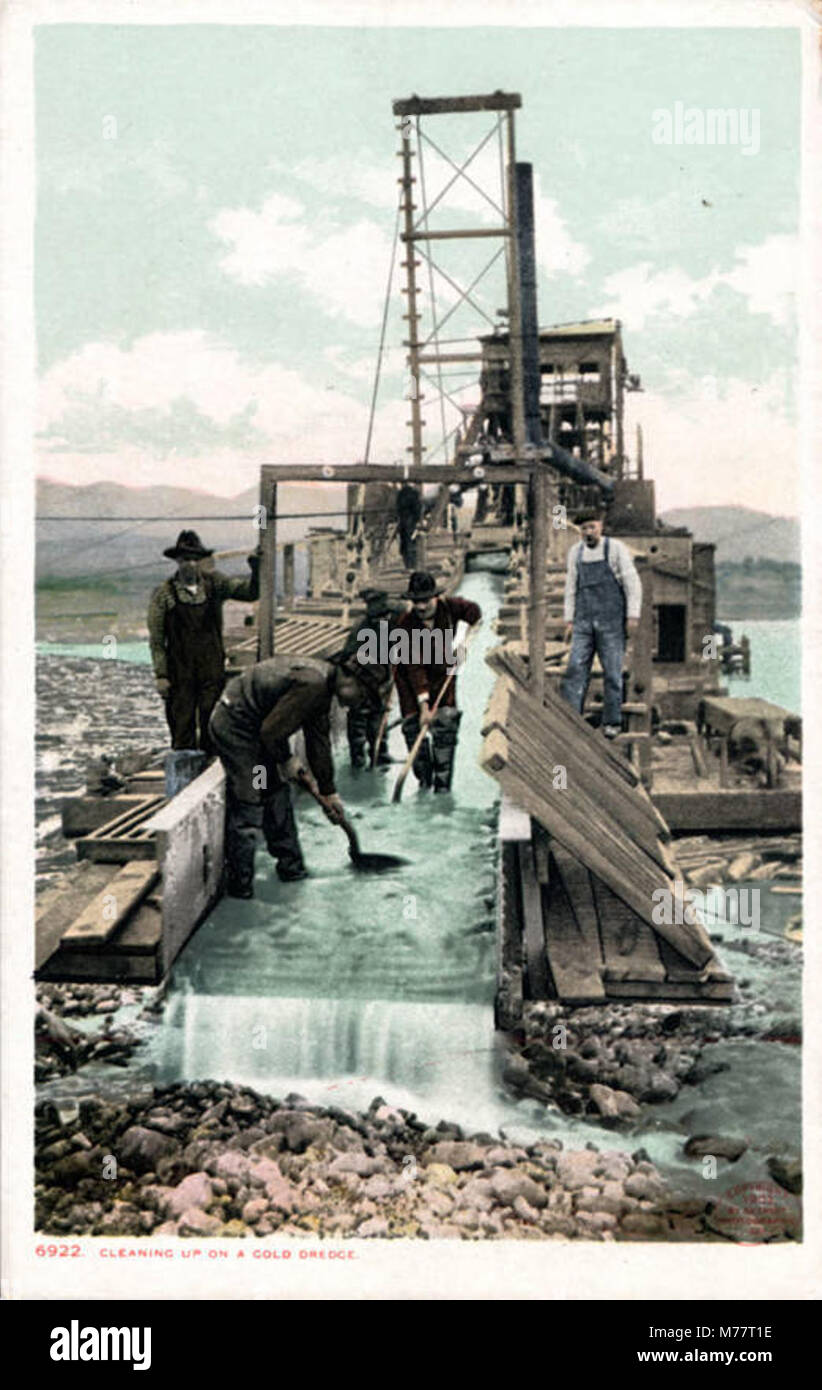 A photograph depicting workers cleaning up on a gold dredge, a type of ...
