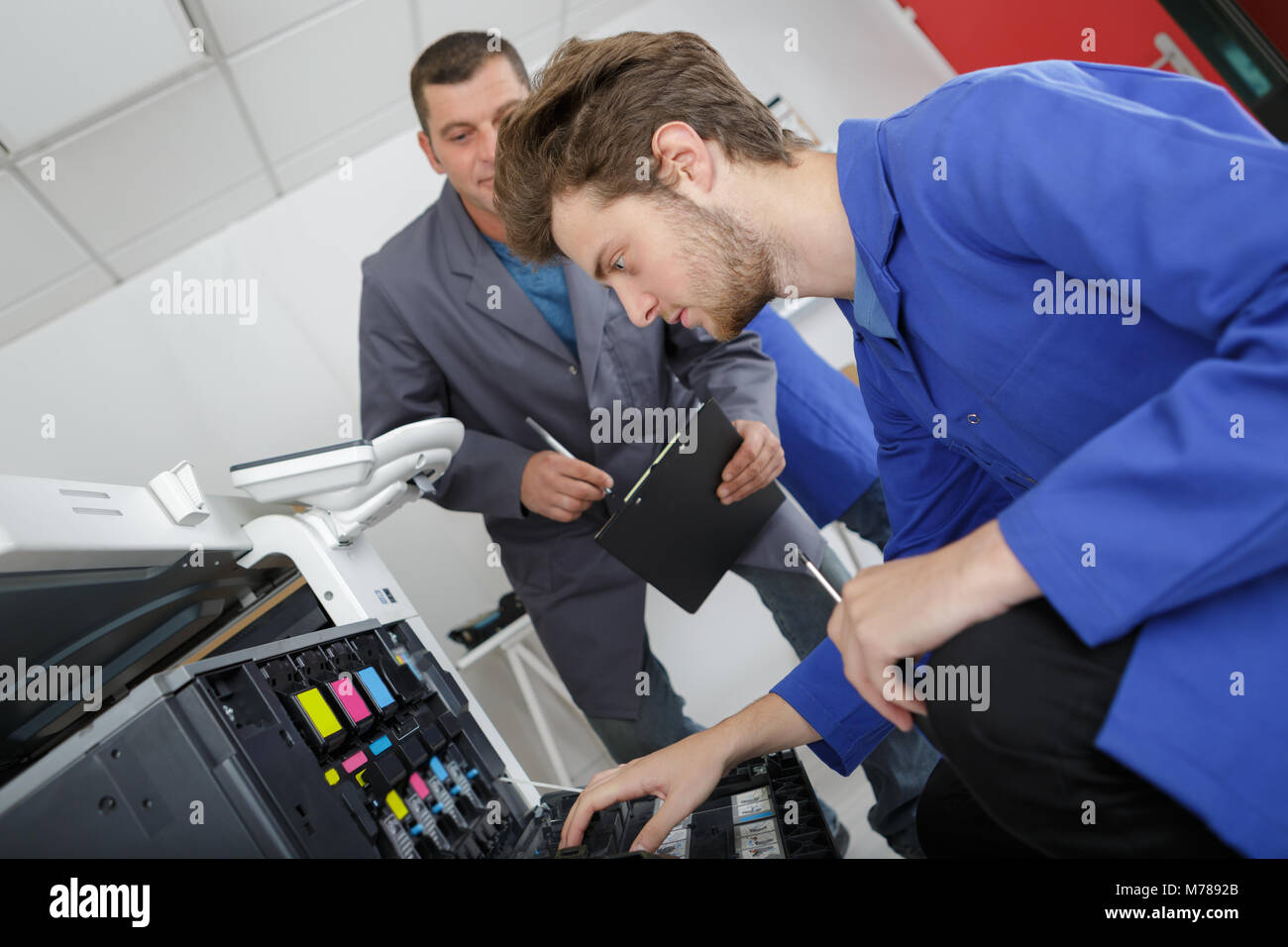 young caucasian man repairing printer in office Stock Photo - Alamy