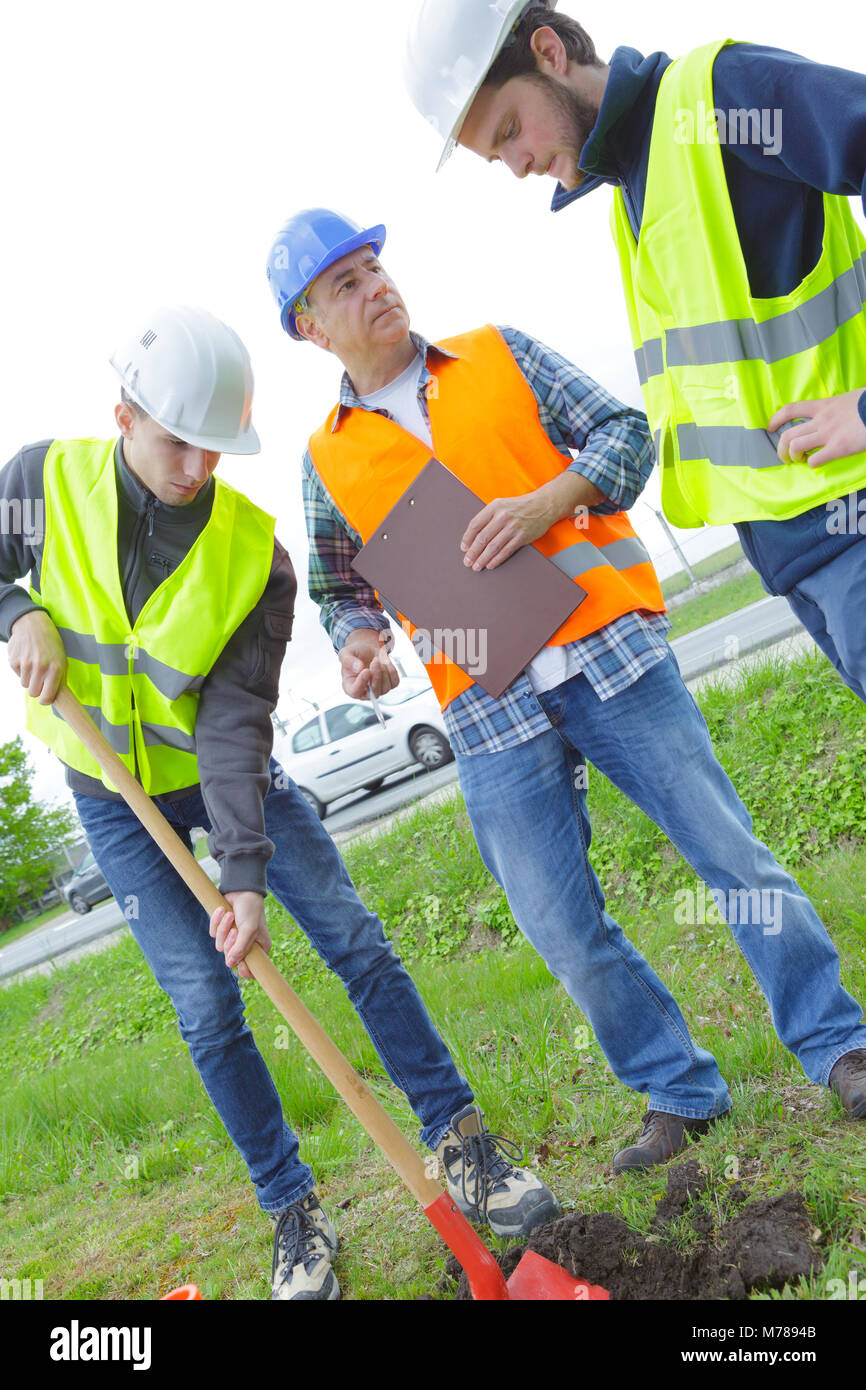 young men digging a hole on the ground Stock Photo - Alamy