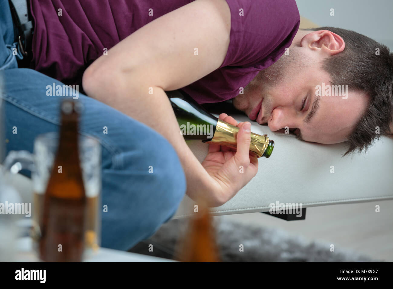 Inebriated man asleep holding empty wine bottle Stock Photo - Alamy