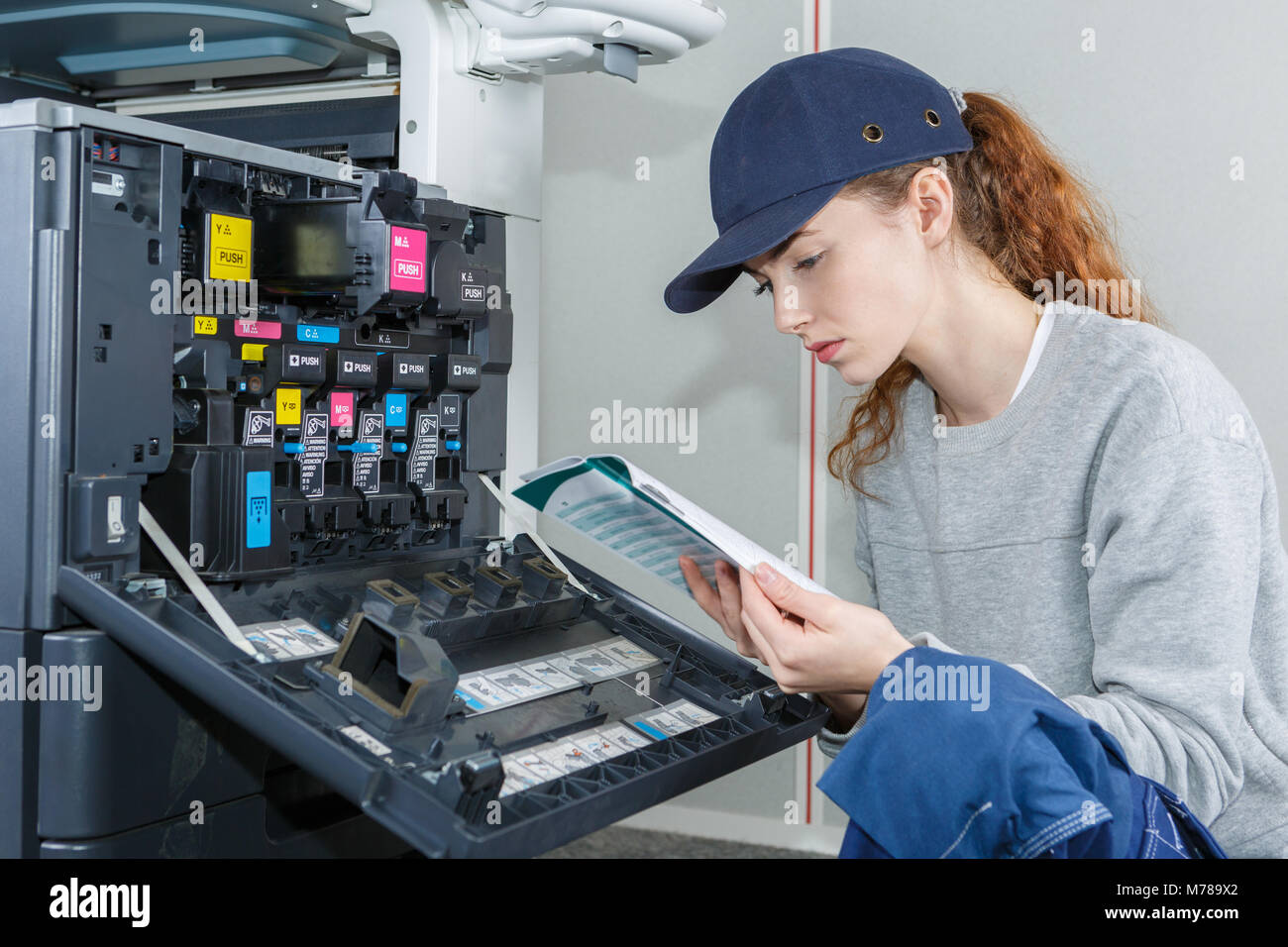 Woman reading instruction manual for photocopier Stock Photo - Alamy