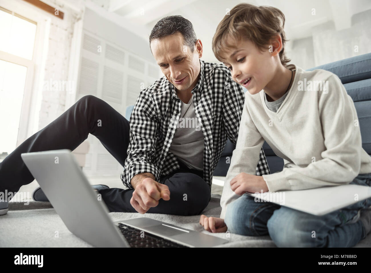 Alert father sitting on the floor with his son Stock Photo - Alamy