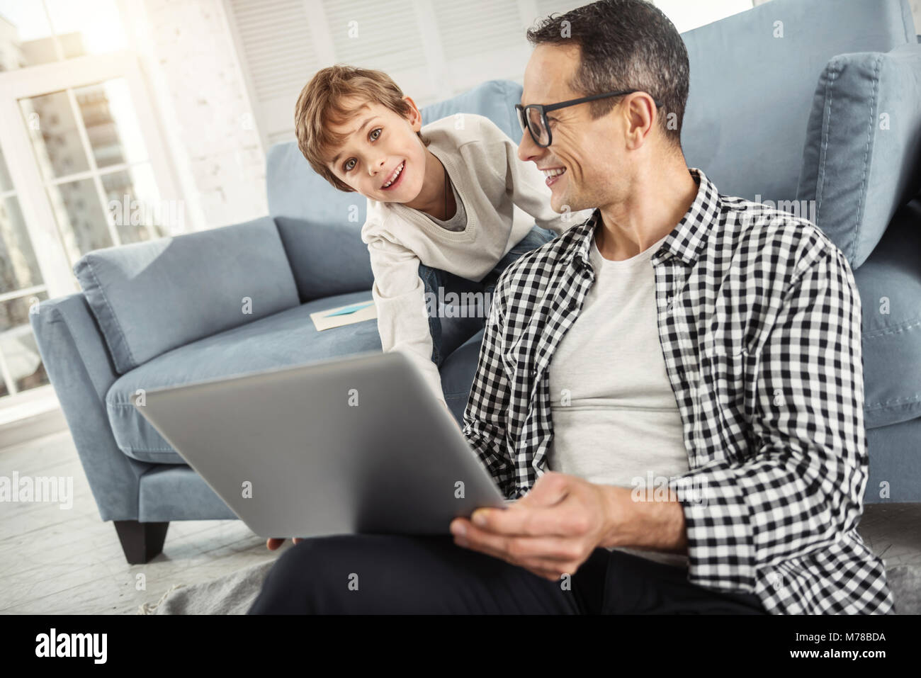 Happy son sitting behind his father Stock Photo - Alamy