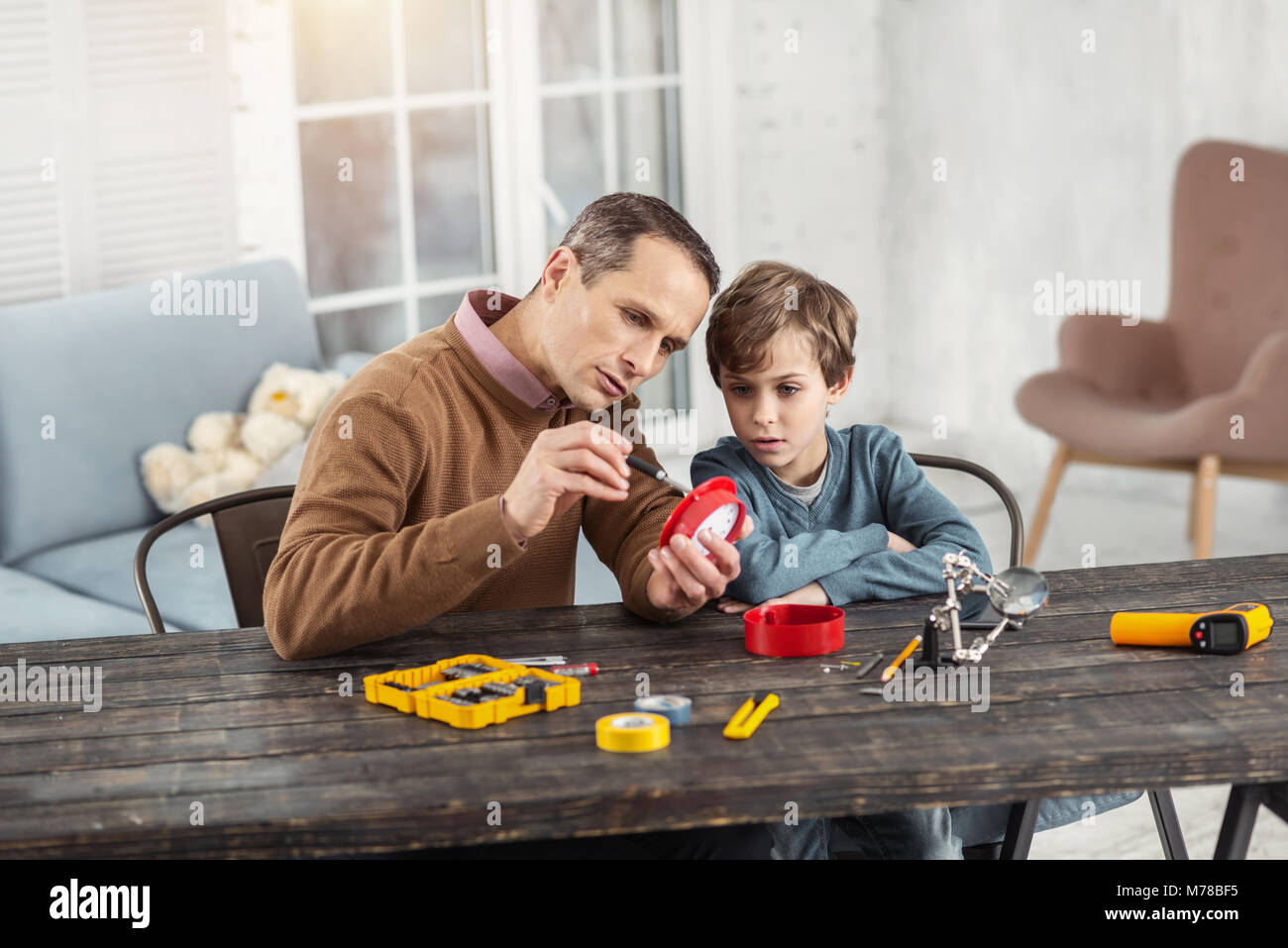 Serious daddy showing instruments to his son Stock Photo - Alamy