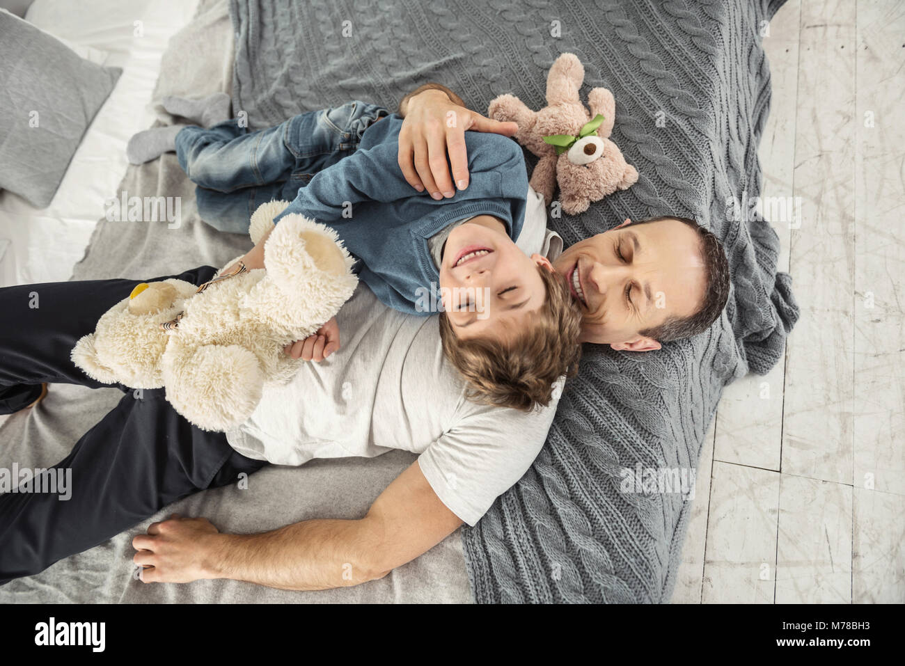 Delighted son and daddy relaxing on bed Stock Photo - Alamy