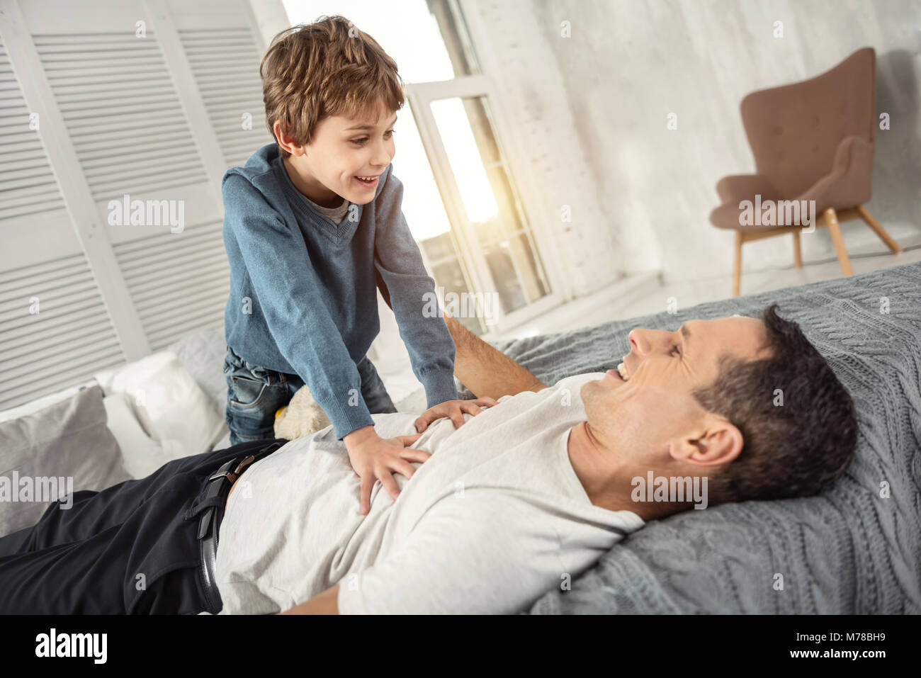 Smiling son and daddy relaxing on bed Stock Photo - Alamy