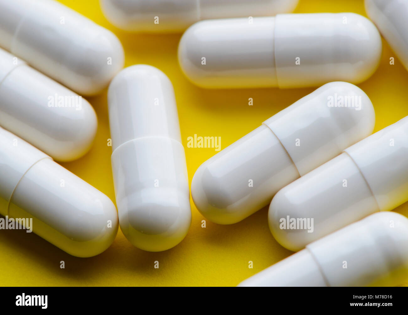 White pill capsule on yellow background Stock Photo - Alamy