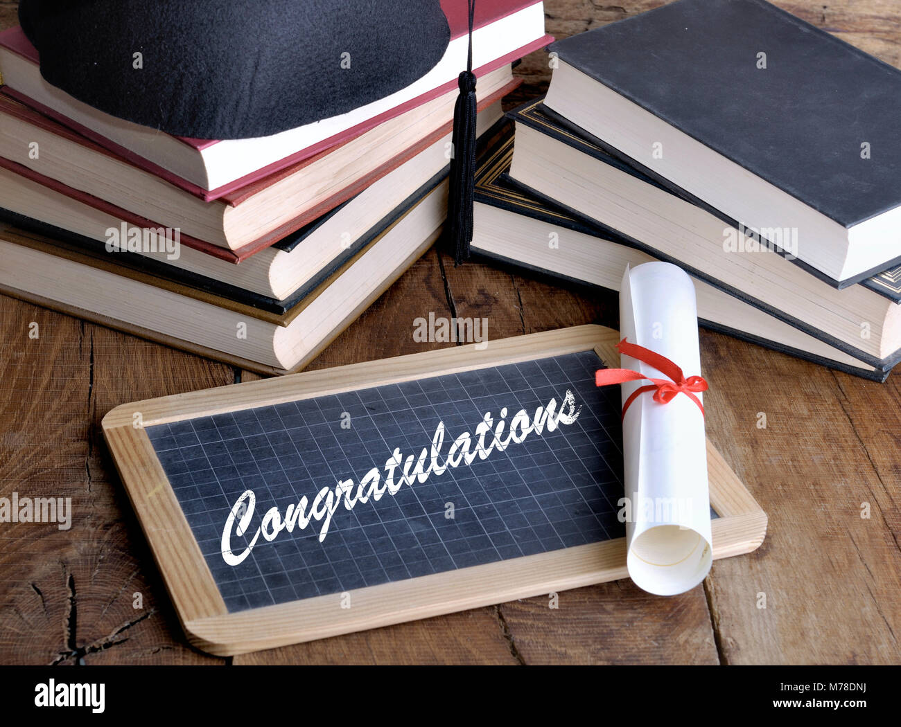 congratulations written on a slate with diploma, books and hat on ...