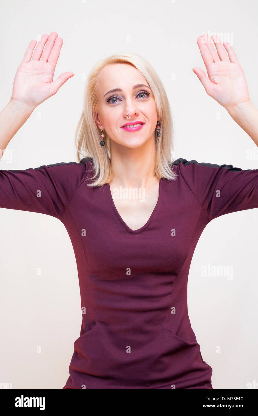Young smiling blonde woman showing raised arms hands up sign on white ...