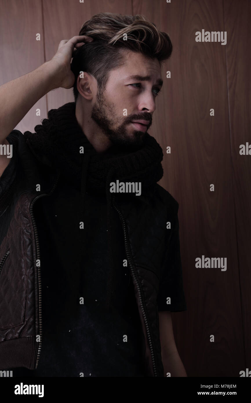 angry man pulling at the gates of his leather jacket against the studio ...